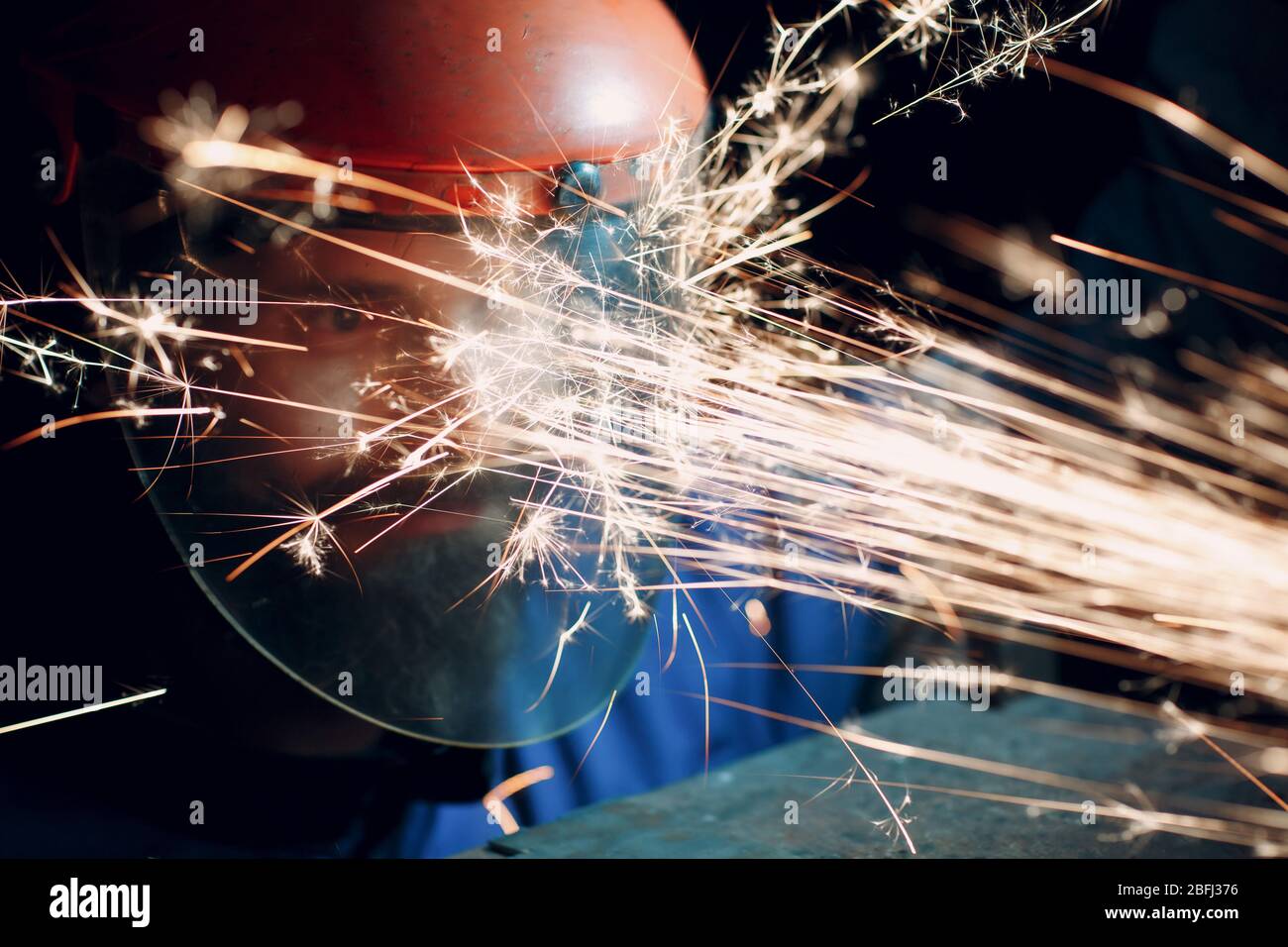 Man worker in transparent protective mask works on metal with circular ...