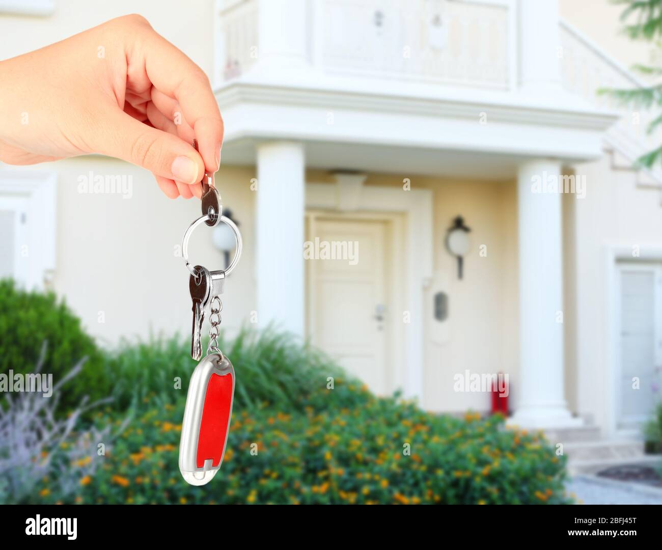 Key in hand on house background, Real estate concept Stock Photo - Alamy