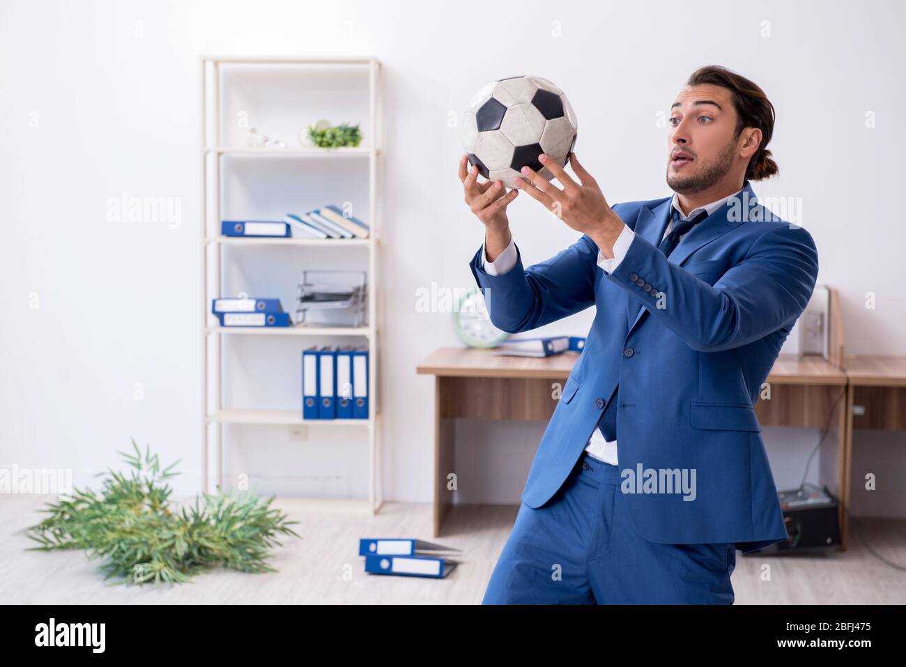 Young employee playing football in the office Stock Photo - Alamy