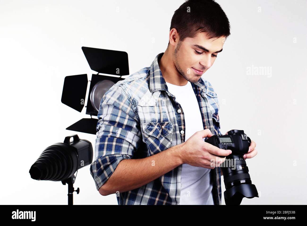 Handsome photographer with camera in photo studio Stock Photo - Alamy