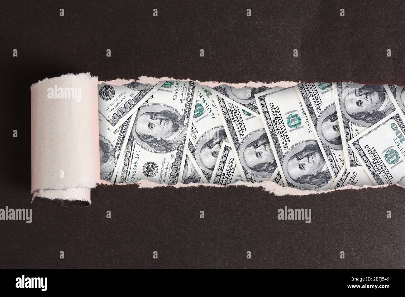 Dollar banknotes through torn black paper Stock Photo - Alamy