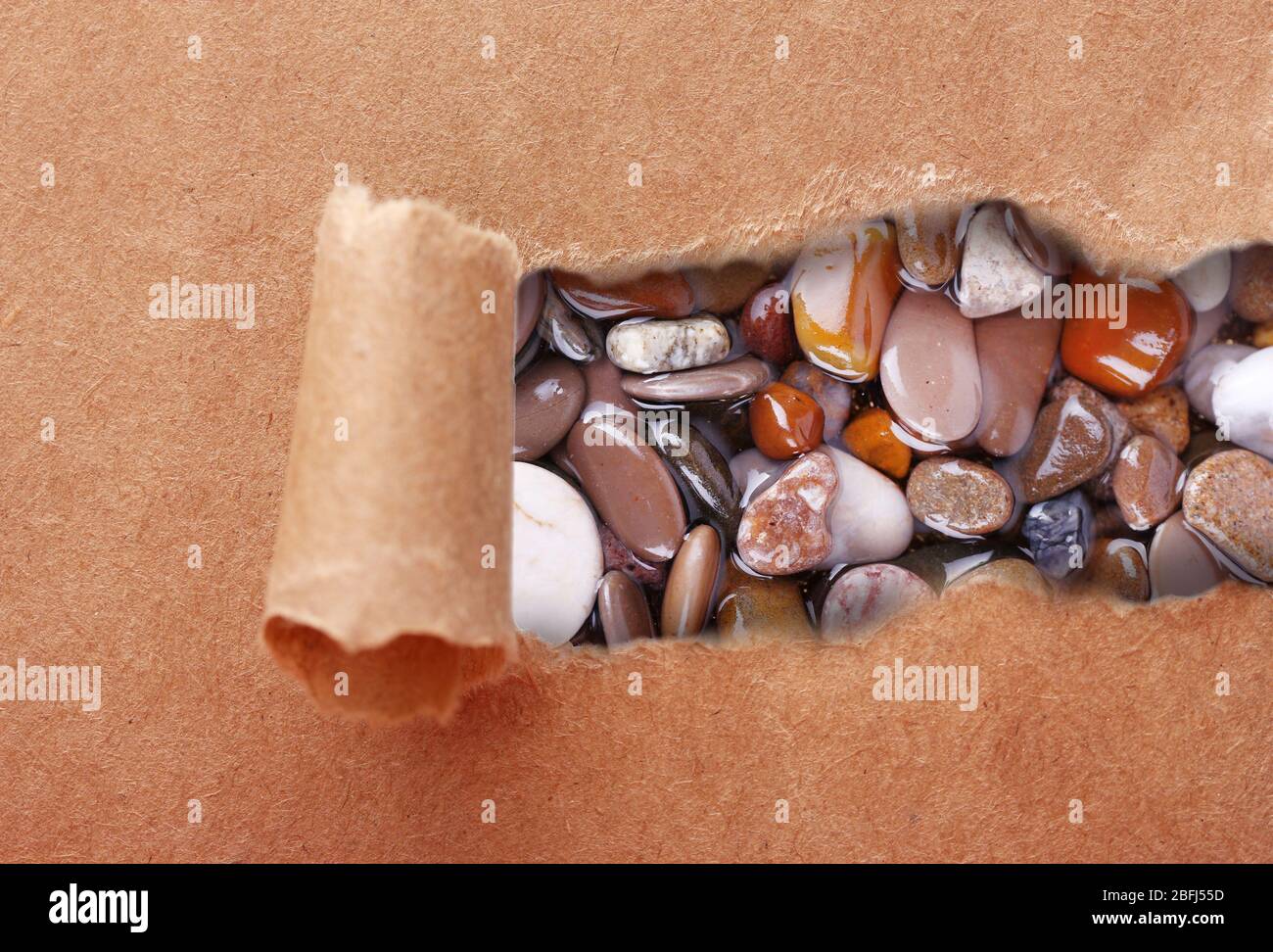 Sea stones through torn brown paper Stock Photo - Alamy