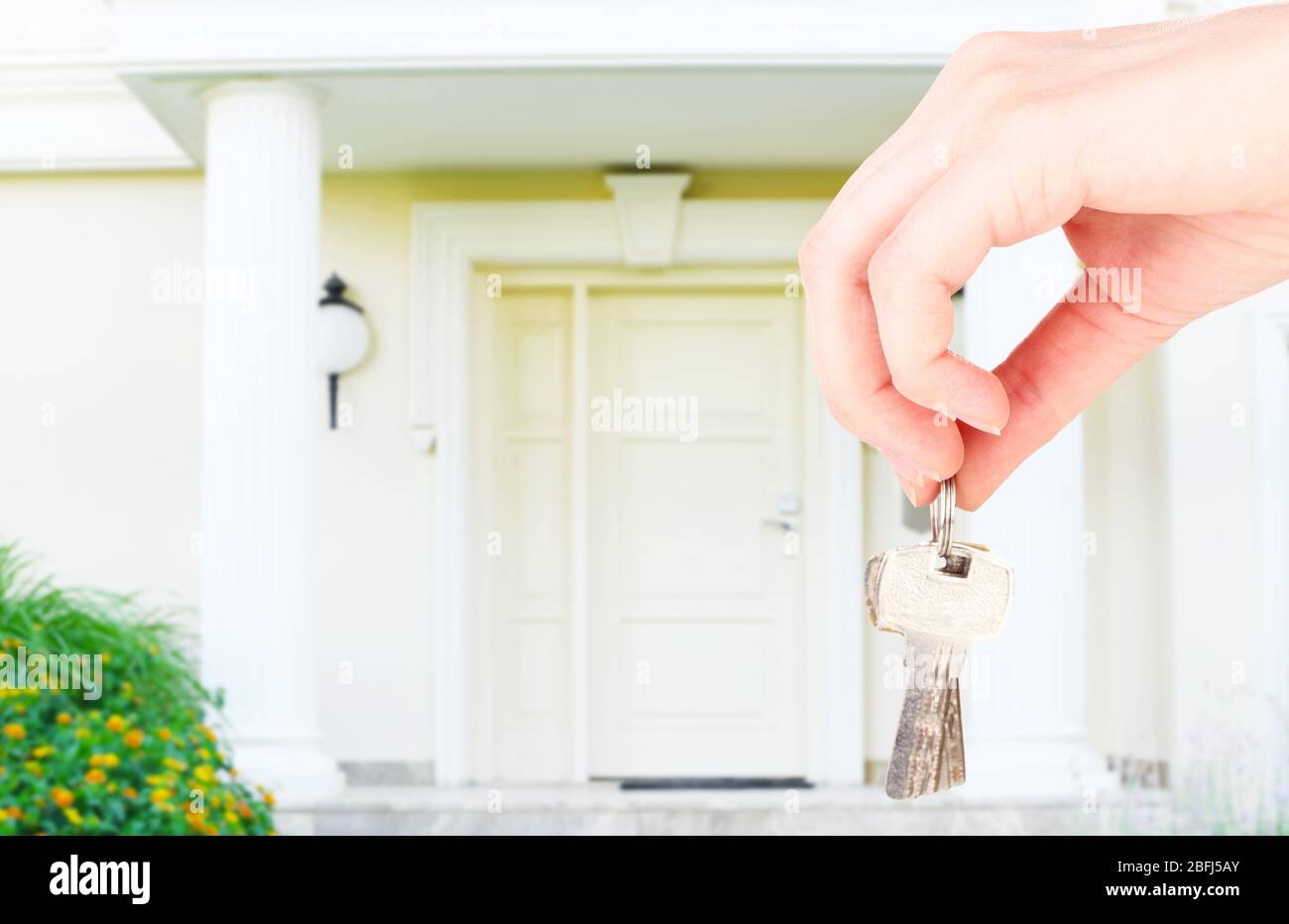 Key in hand on house background, Real estate concept Stock Photo - Alamy