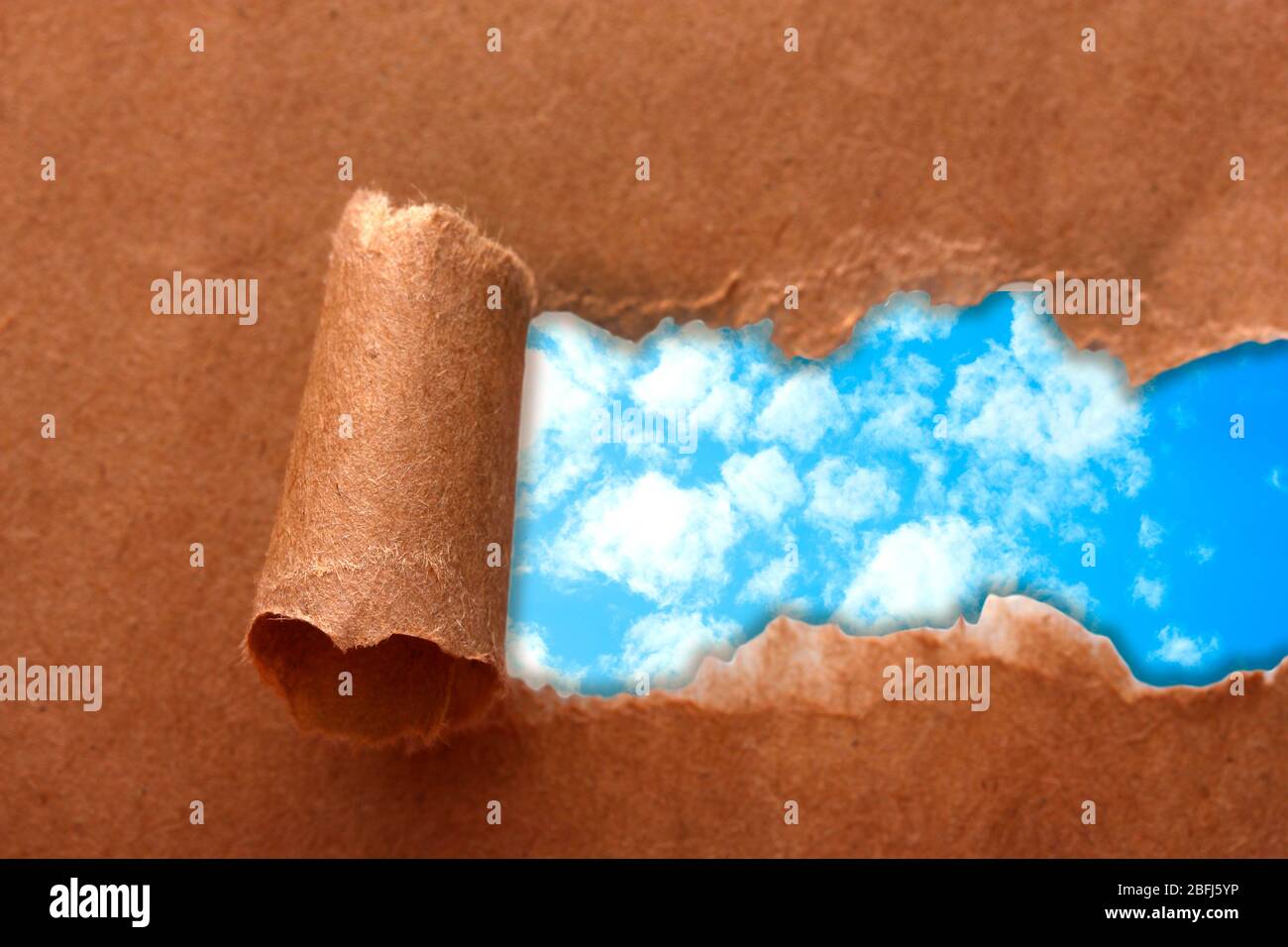 Blue sky background with clouds through torn craft paper Stock Photo ...