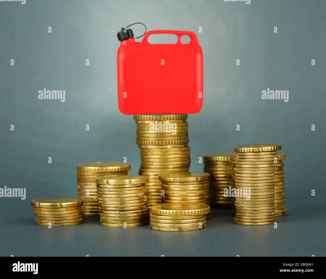 Fuel canister on stack of coins on gray background Stock Photo - Alamy