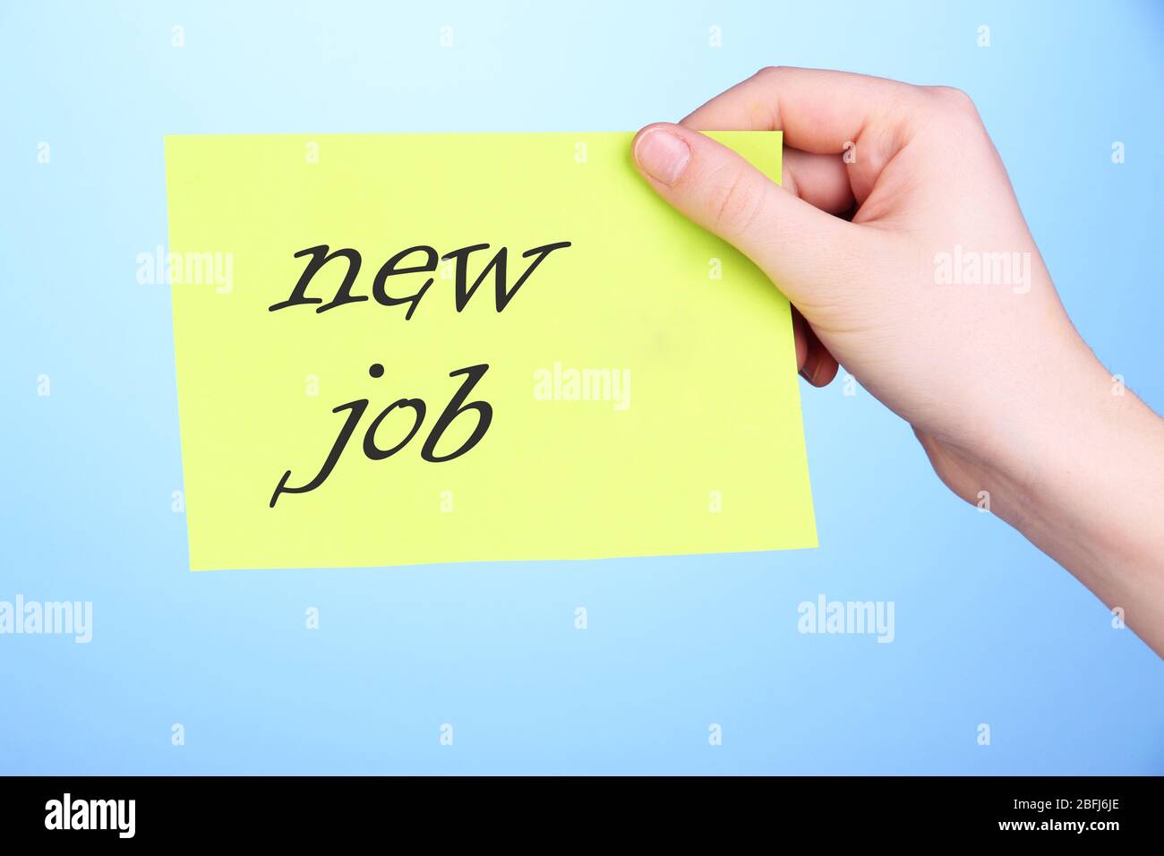New Job text on piece of paper in hand on blue background Stock Photo ...