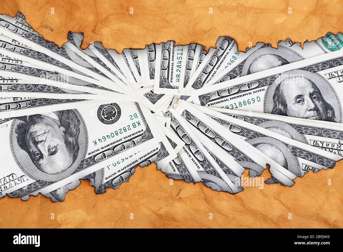Dollars through torn craft paper Stock Photo - Alamy