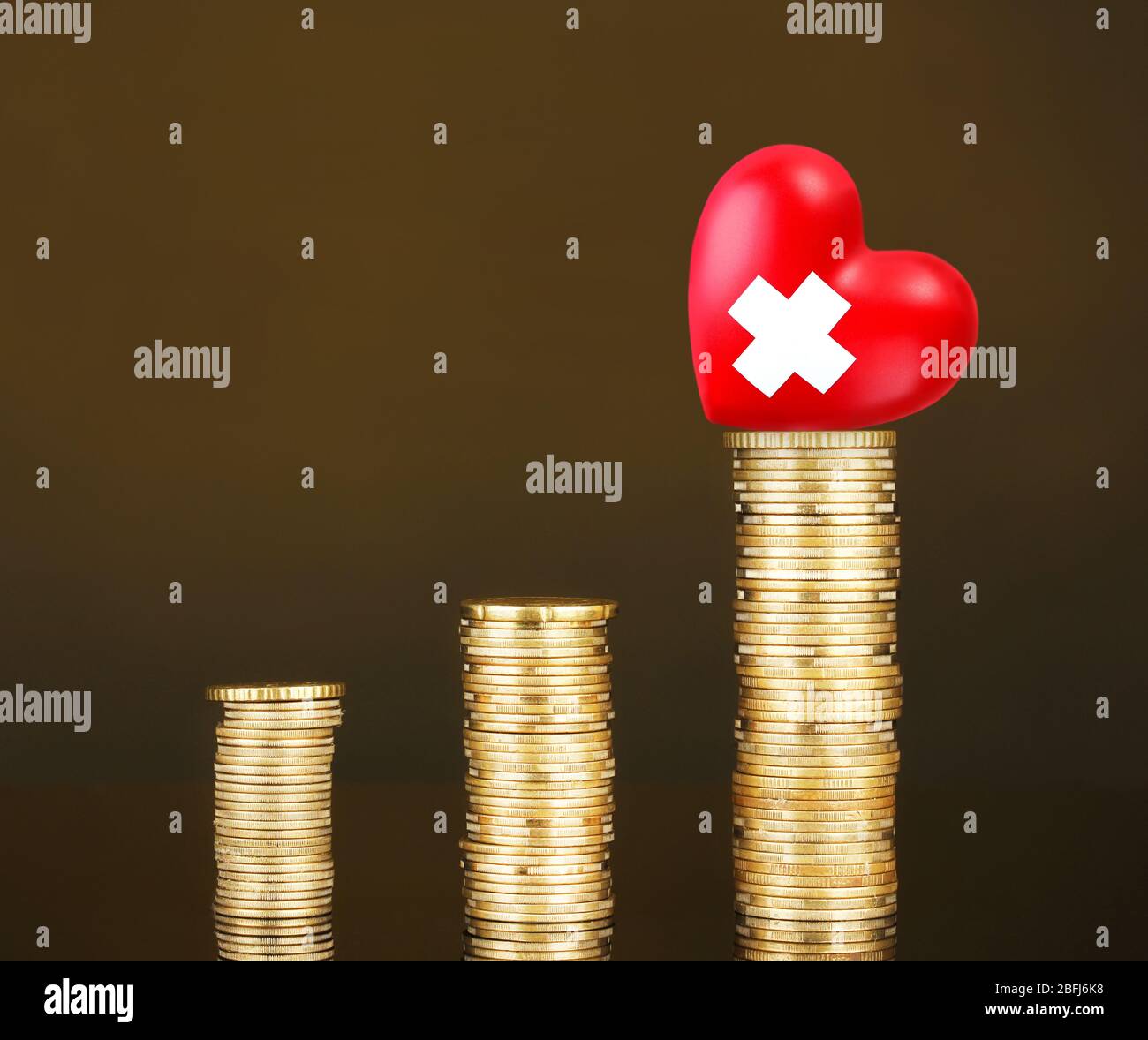Red heart with cross sign on stack of coins on brown background Stock ...