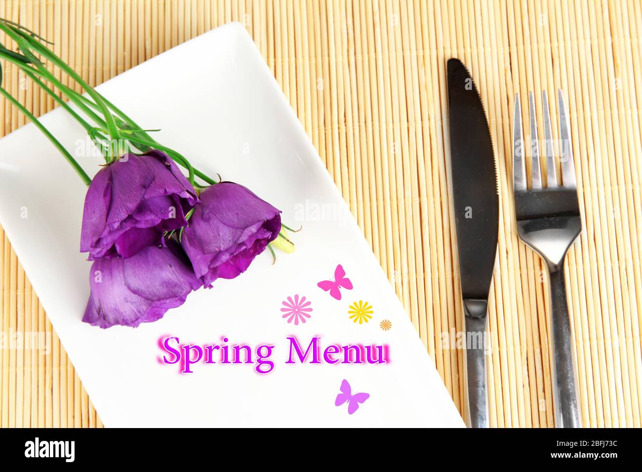 Plate with text "Spring Menu", fork and knife on bamboo mat background ...