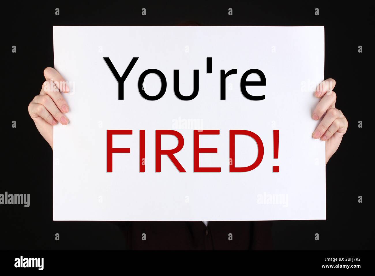 Sheet of paper with text You're Fired in hands isolated on black Stock ...