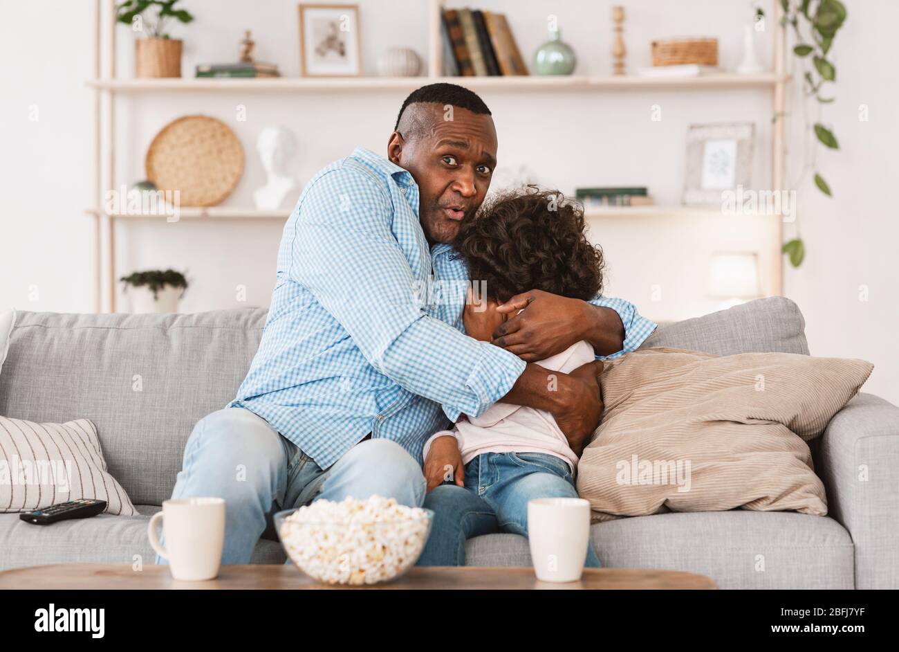 Family entertainments. African American grandpa hugging his scared ...