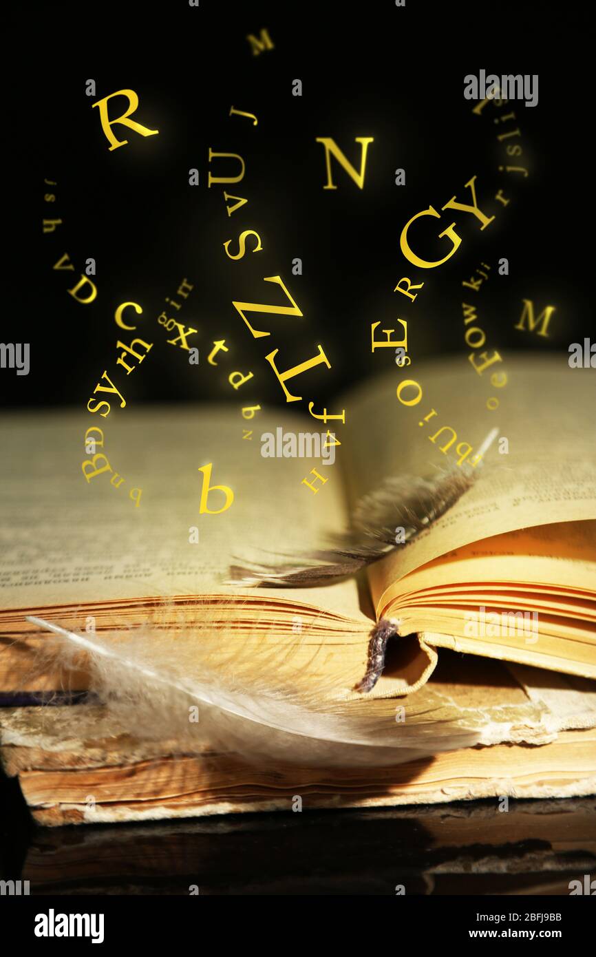 Open book with flying letters on table on dark background Stock Photo ...