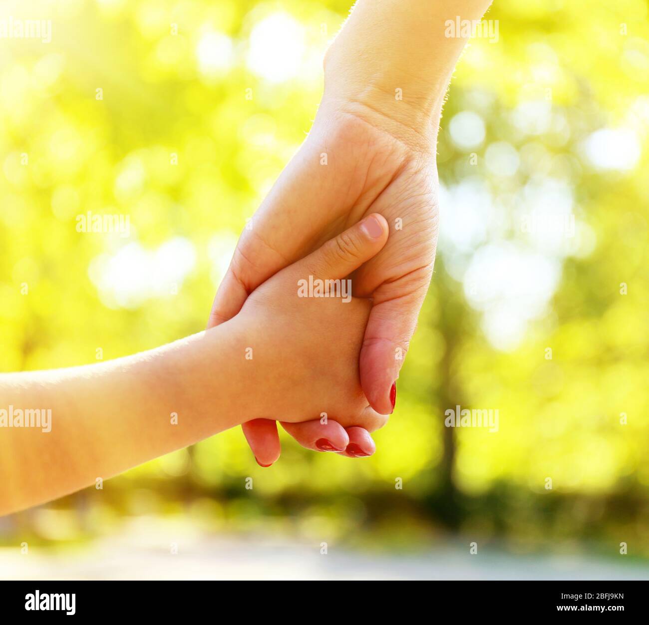 Mom and daughter hands on sunny nature background Stock Photo - Alamy