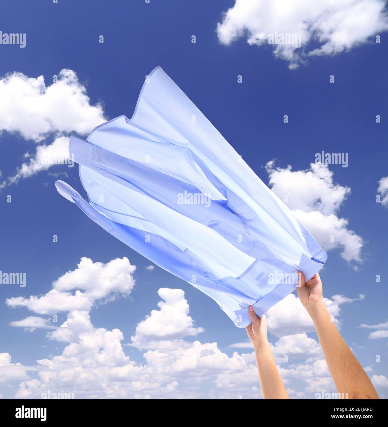 Hands holding flying shirt on sky background Stock Photo - Alamy