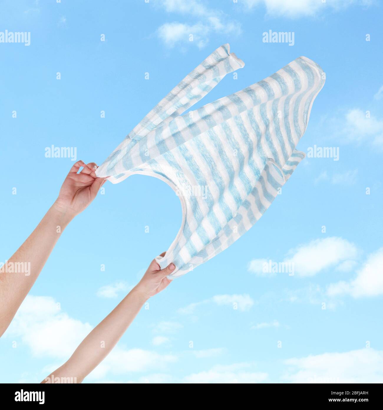 Hands holding flying shirt on sky background Stock Photo - Alamy