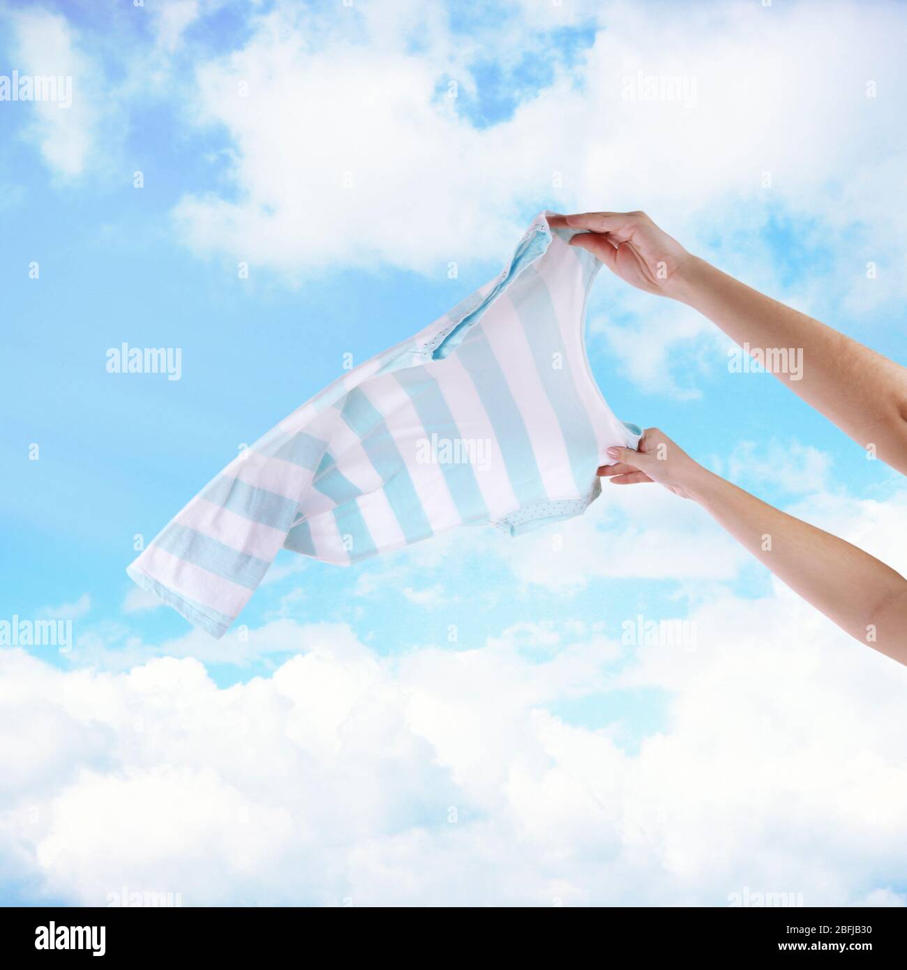 Hands holding flying shirt on sky background Stock Photo - Alamy