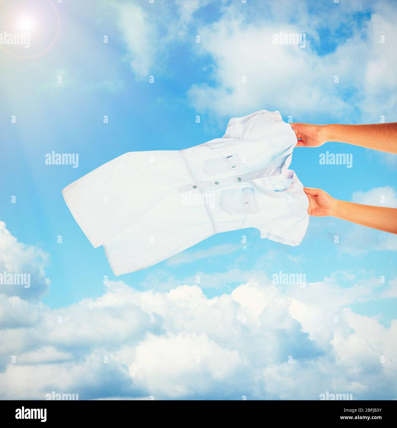 Hands holding flying shirt on sky background Stock Photo - Alamy