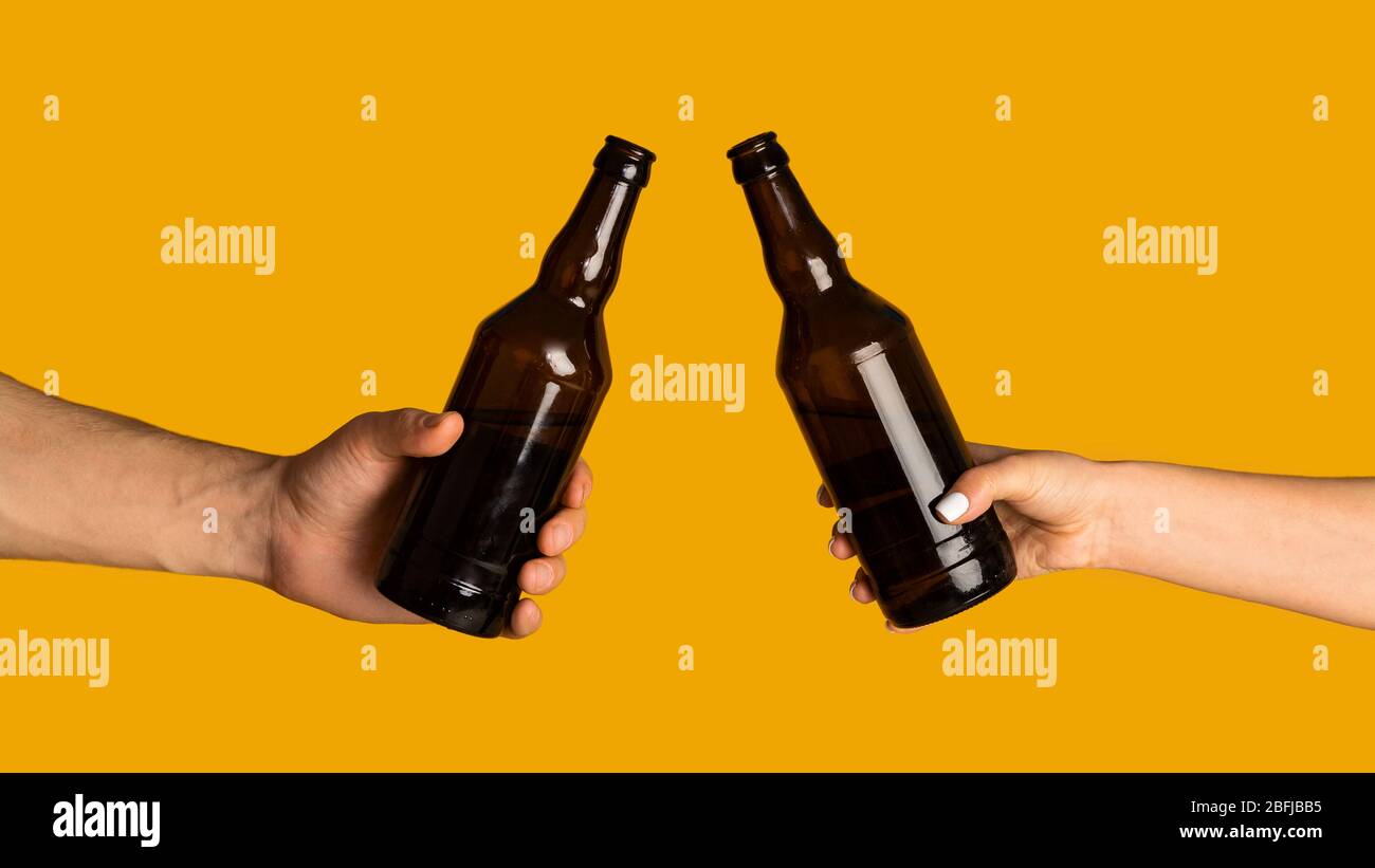 Hands of man and woman clinking bottles of beer, celebrating something ...