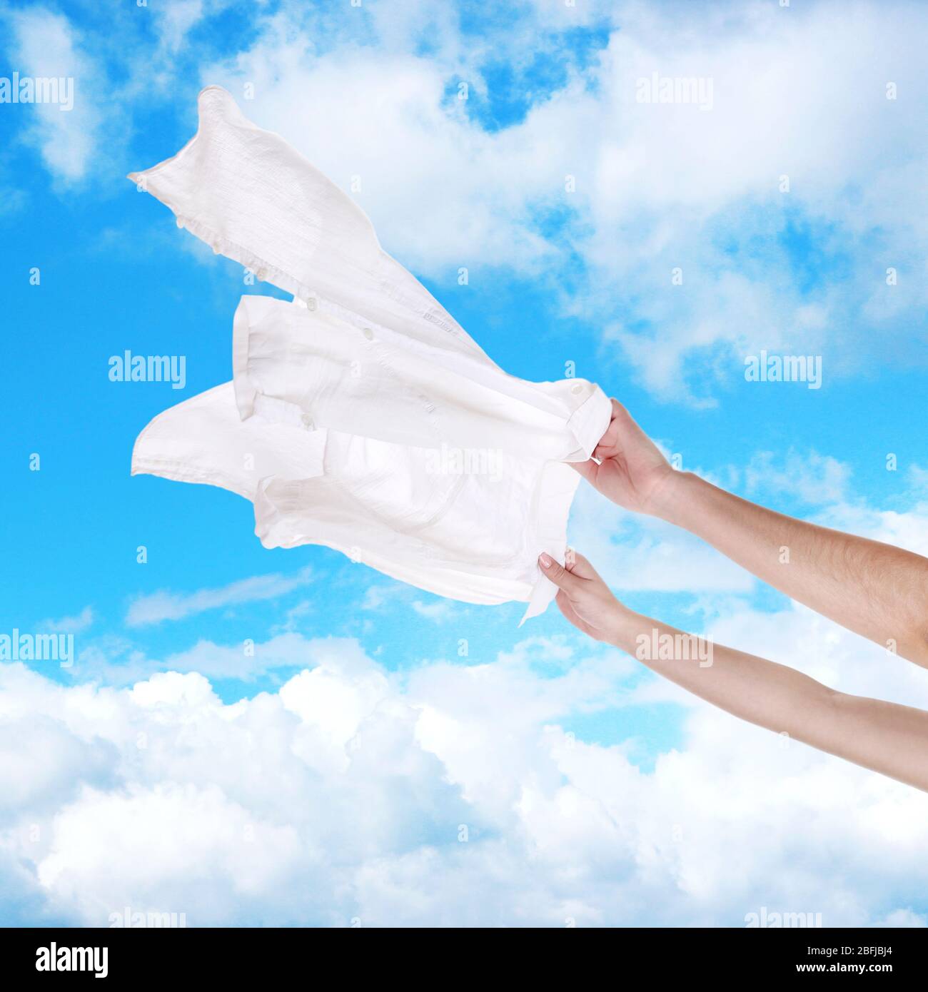 Hands holding flying shirt on sky background Stock Photo - Alamy
