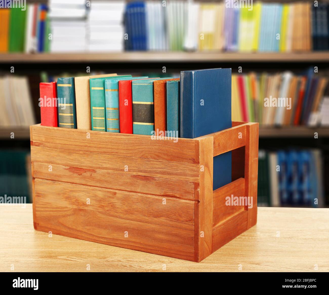 Books in wooden crate on bookshelves background Stock Photo - Alamy