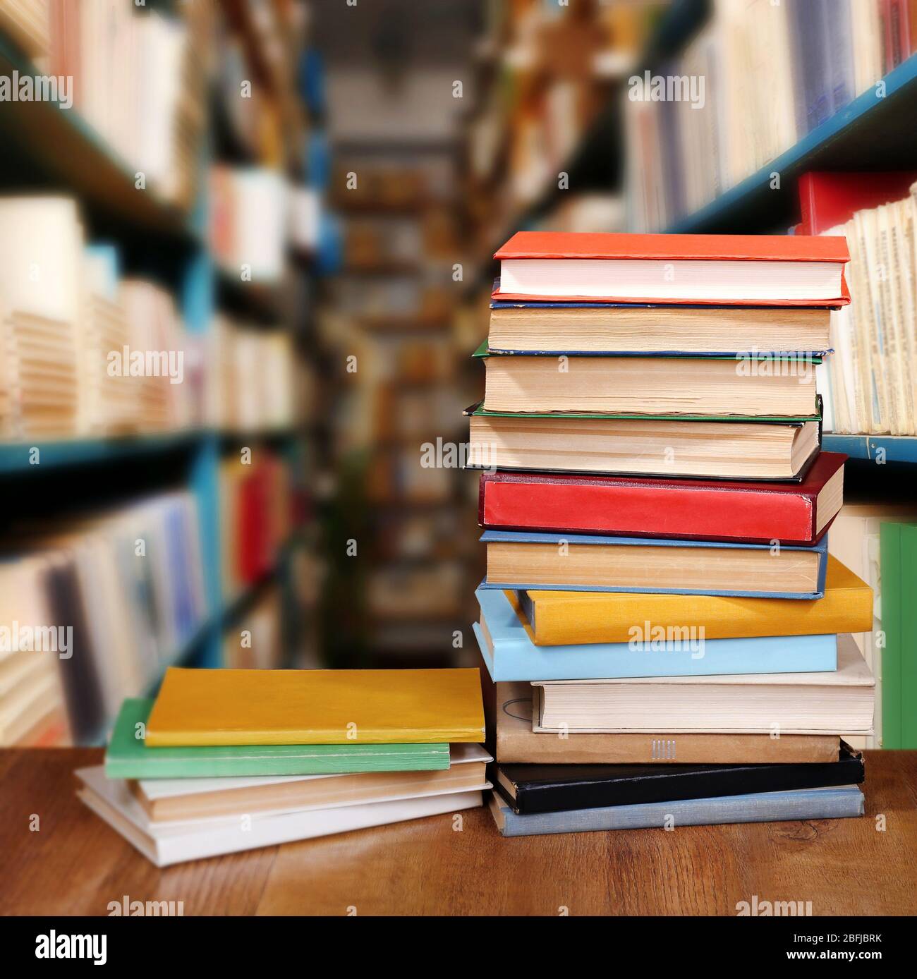 Stack of books on table on bookshelves background Stock Photo - Alamy