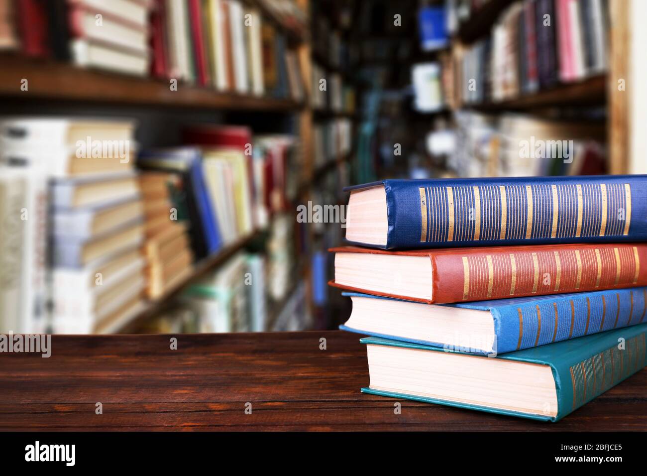 Stack of books on table on bookshelves background Stock Photo - Alamy