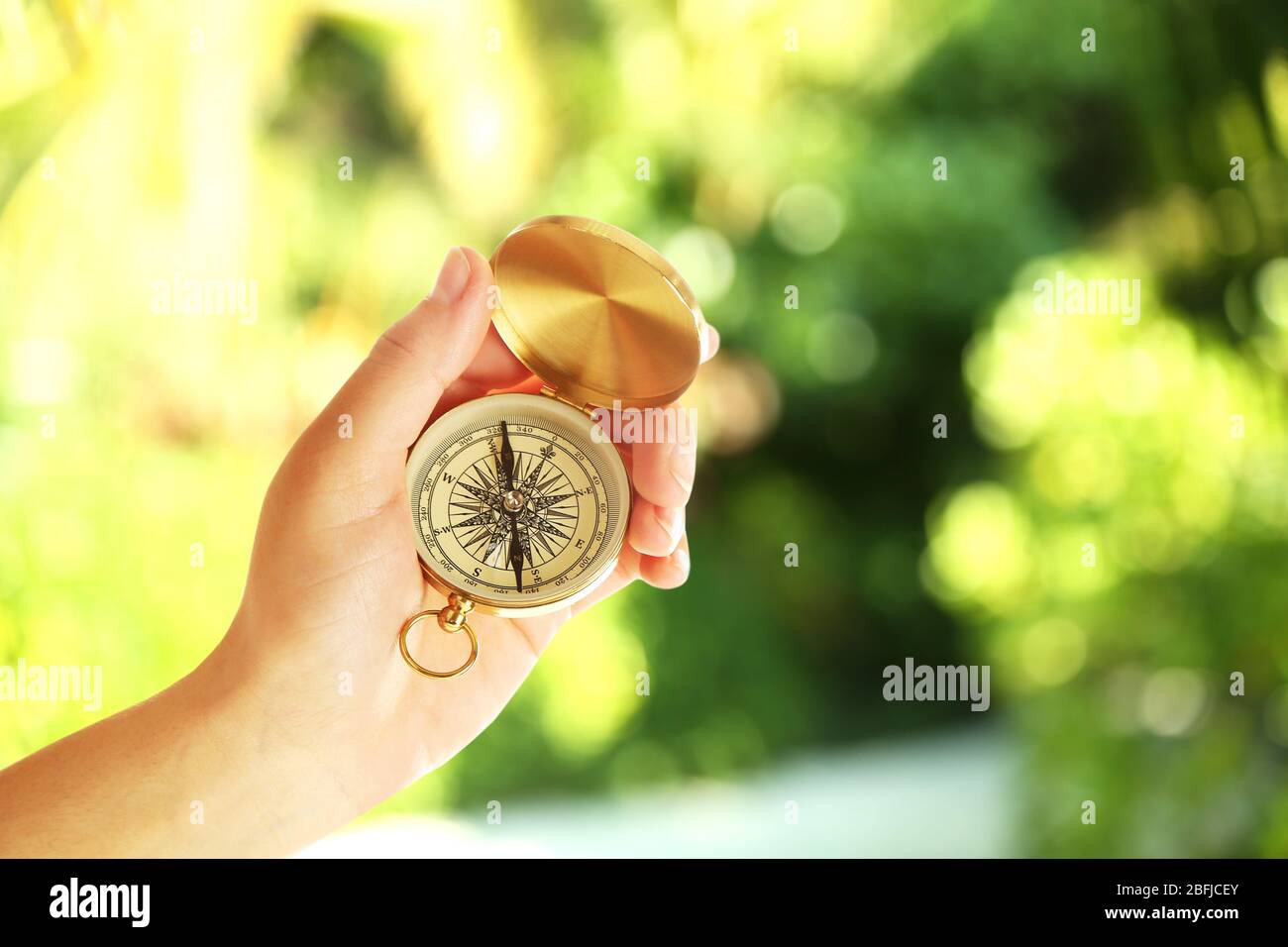 Human hand with compass on nature background Stock Photo - Alamy