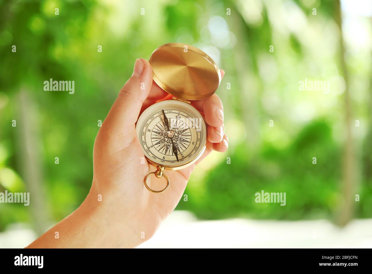Human hand with compass on nature background Stock Photo - Alamy