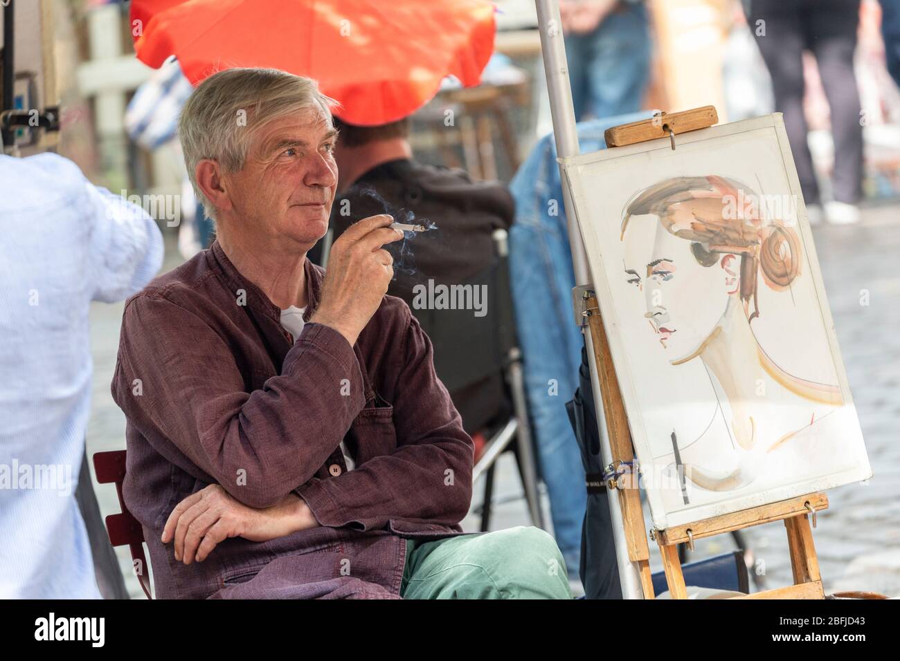 Portrait of a male artist smoking beside one of his artworks sitting on ...