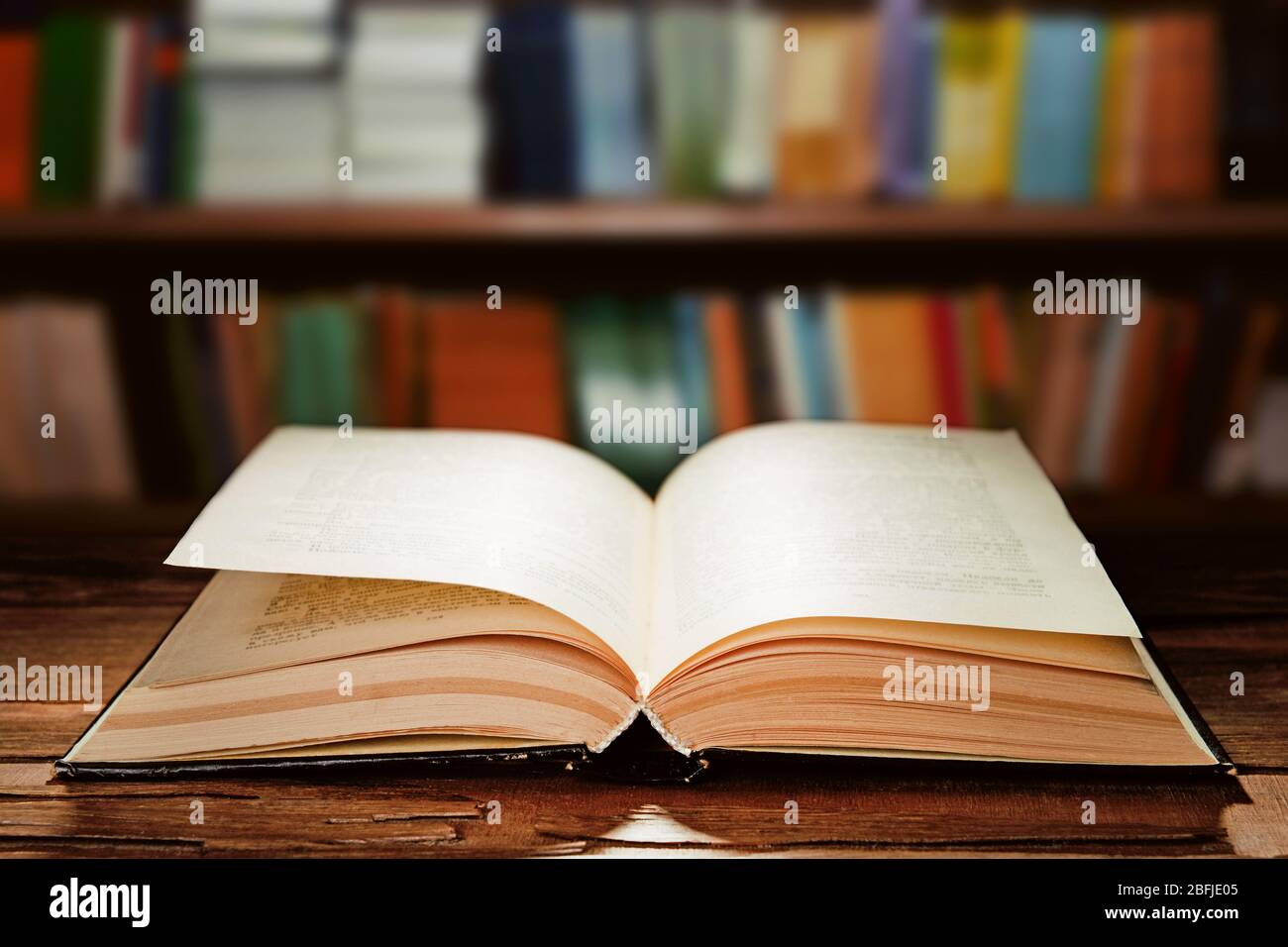 Open book on bookshelves background Stock Photo - Alamy
