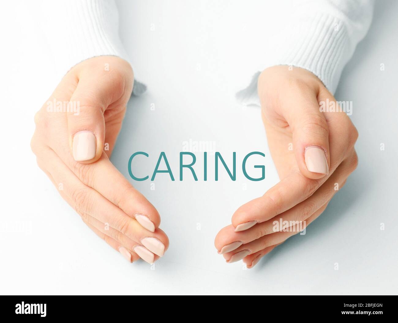 Female hands with word caring on light background Stock Photo - Alamy