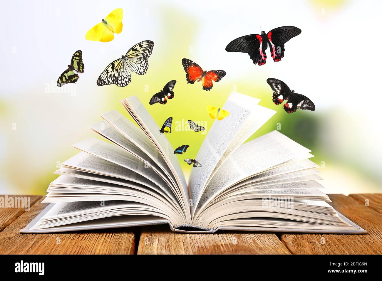 Open book on wooden table and butterflies on natural background Stock ...
