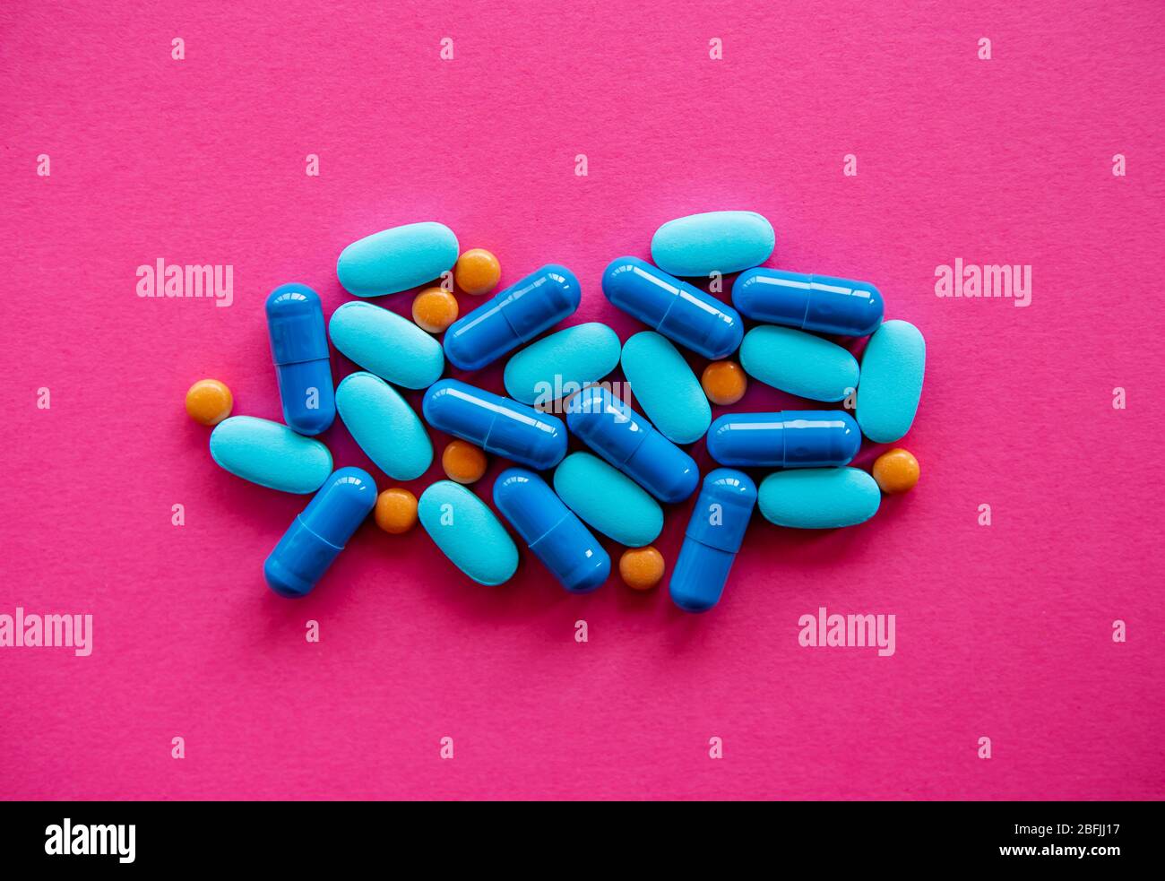 Multi colored medical pills in flat lay on pink background.Pile of ...