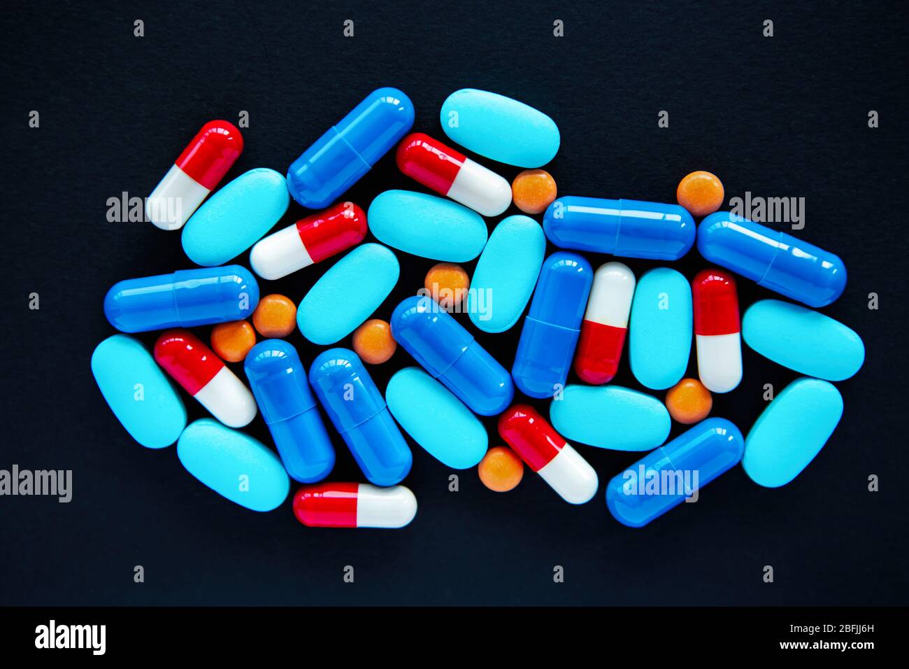 Multi colored medical pills in flat lay on black background.Pile of ...