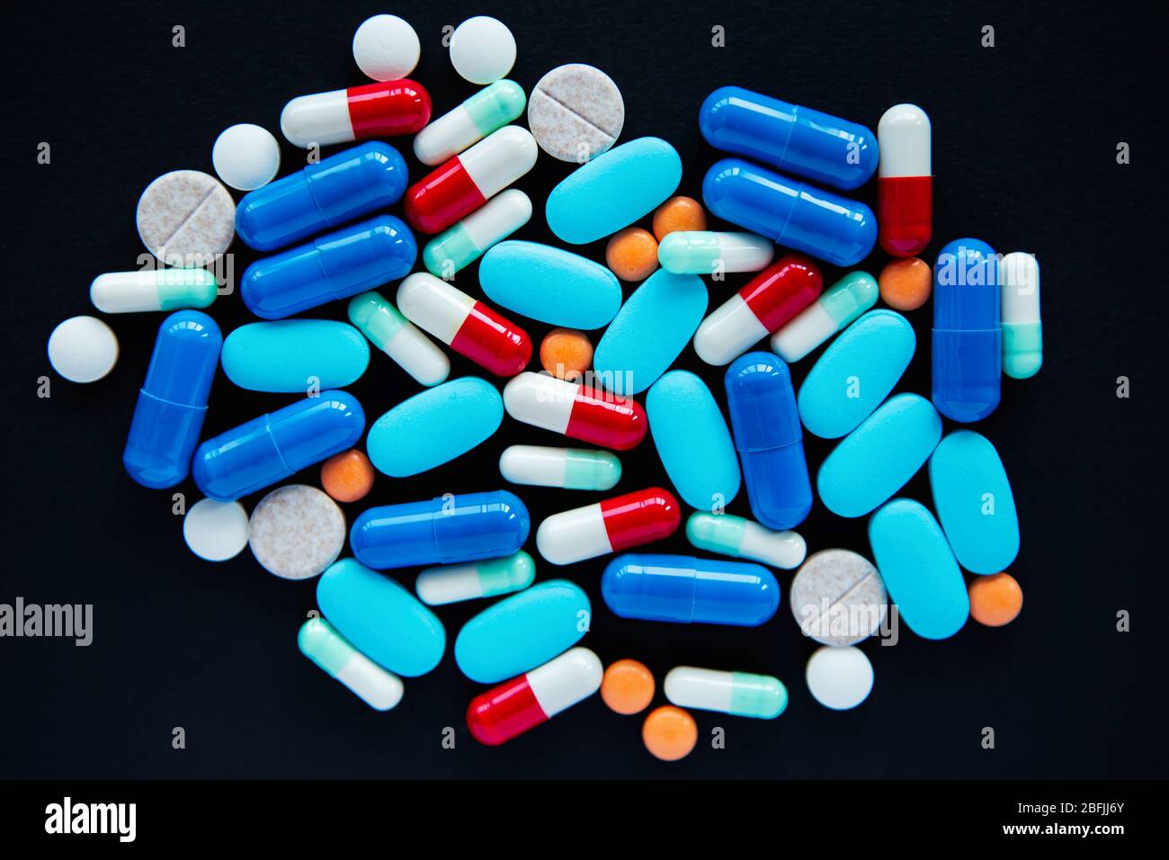 Multi colored medical pills in flat lay on black background.Pile of ...
