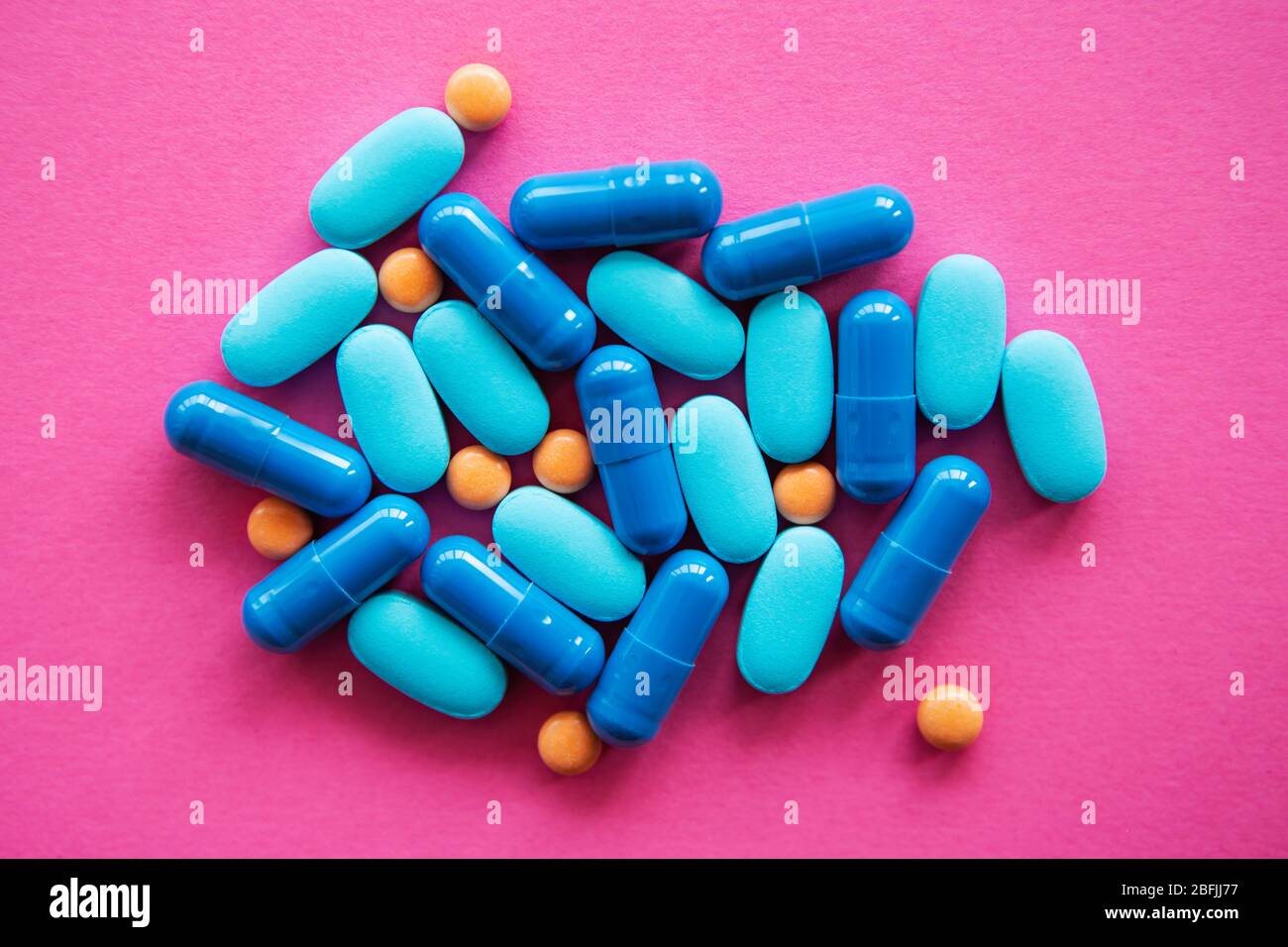 Multi colored medical pills in flat lay on pink background.Pile of ...