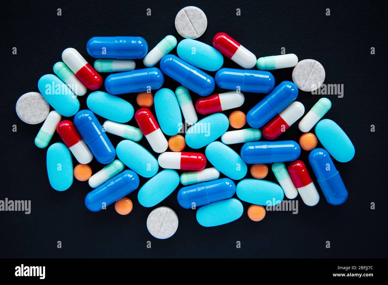 Multi colored medical pills in flat lay on black background.Pile of ...