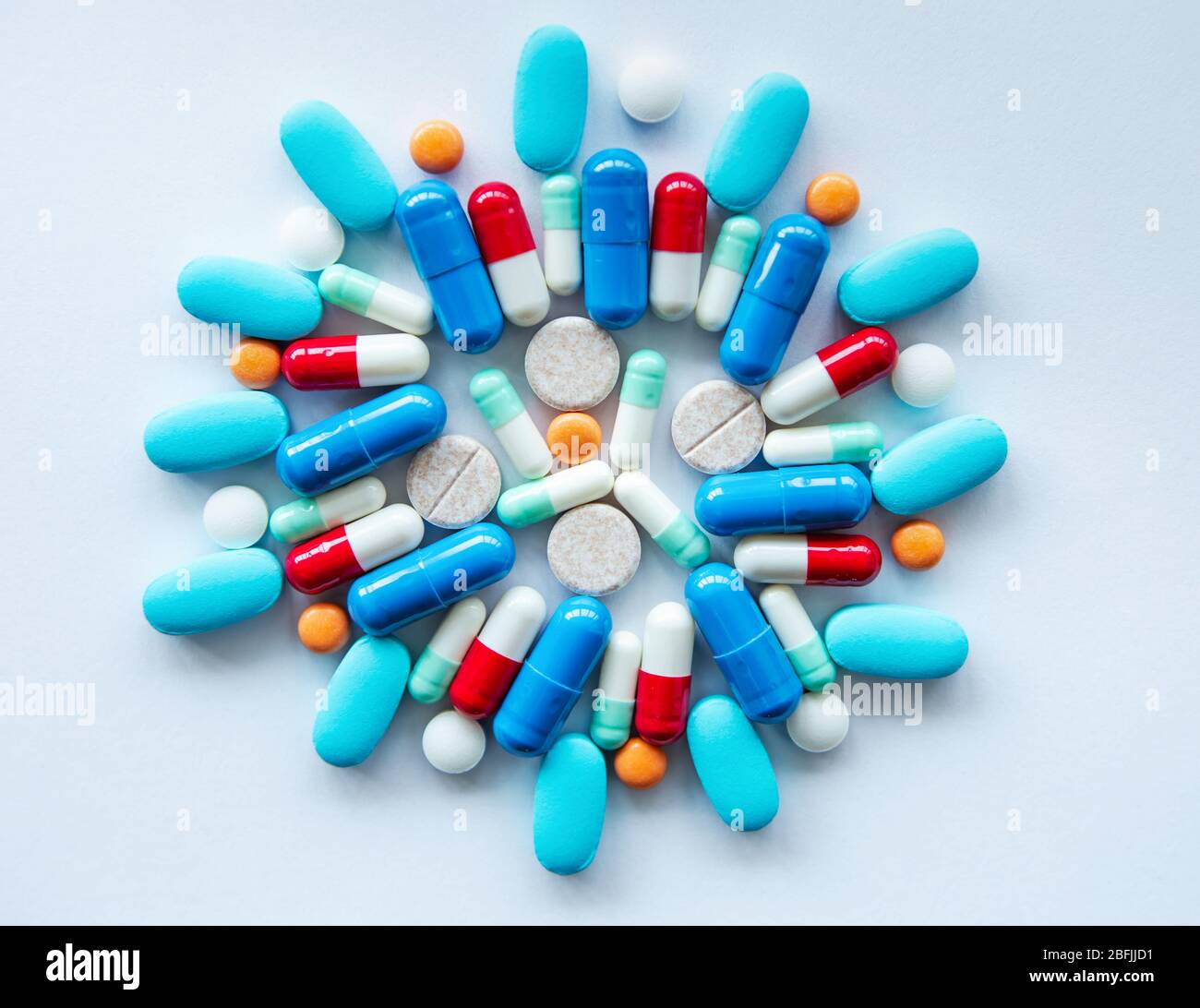 Multi colored medical pills in flat lay on light blue background.Pile ...