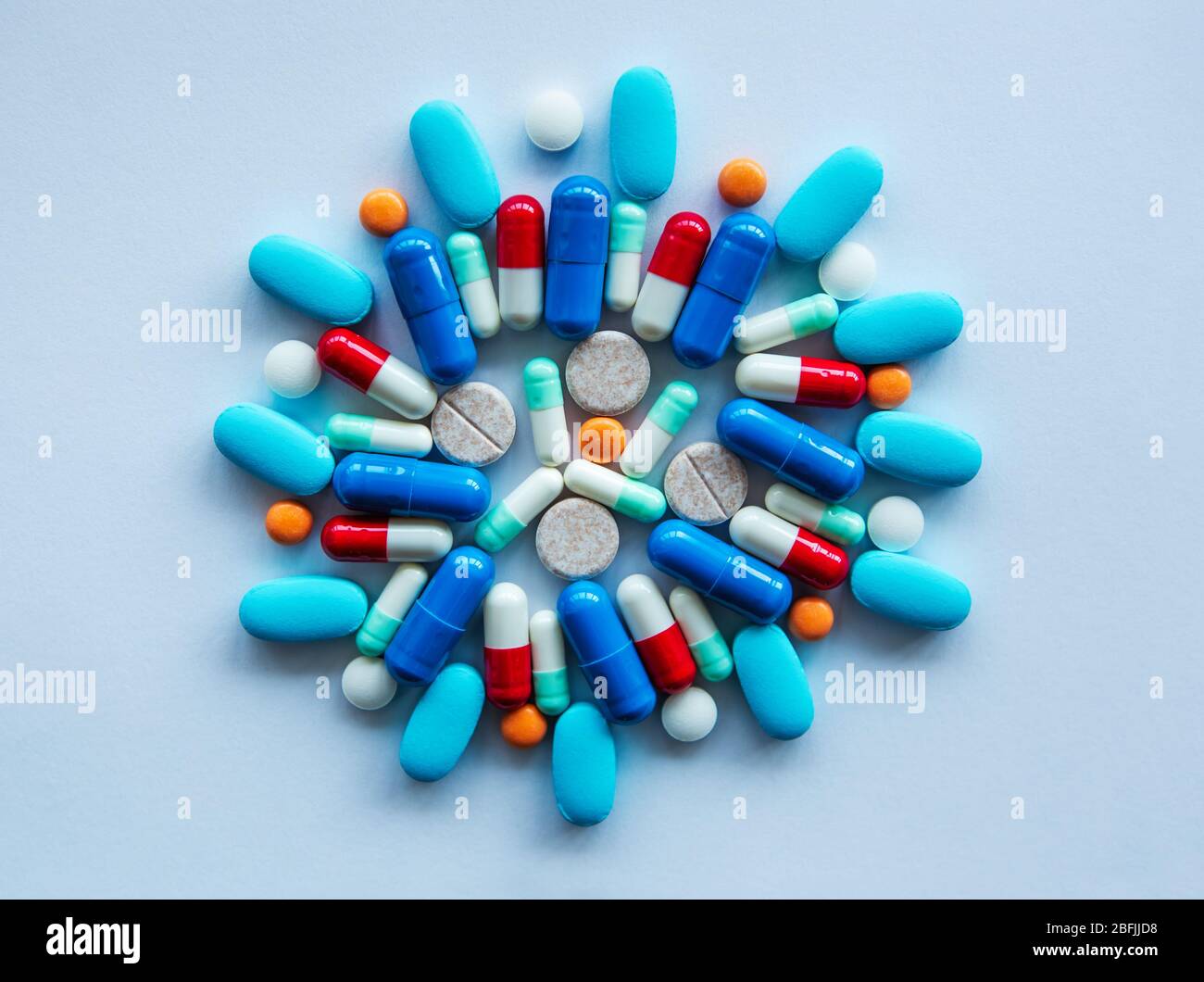 Multi colored medical pills in flat lay on light blue background.Pile ...