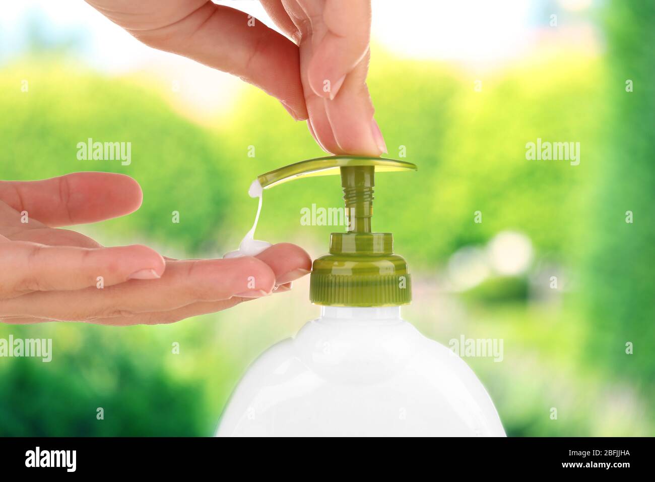 Female hands using liquid soap on nature background Stock Photo - Alamy