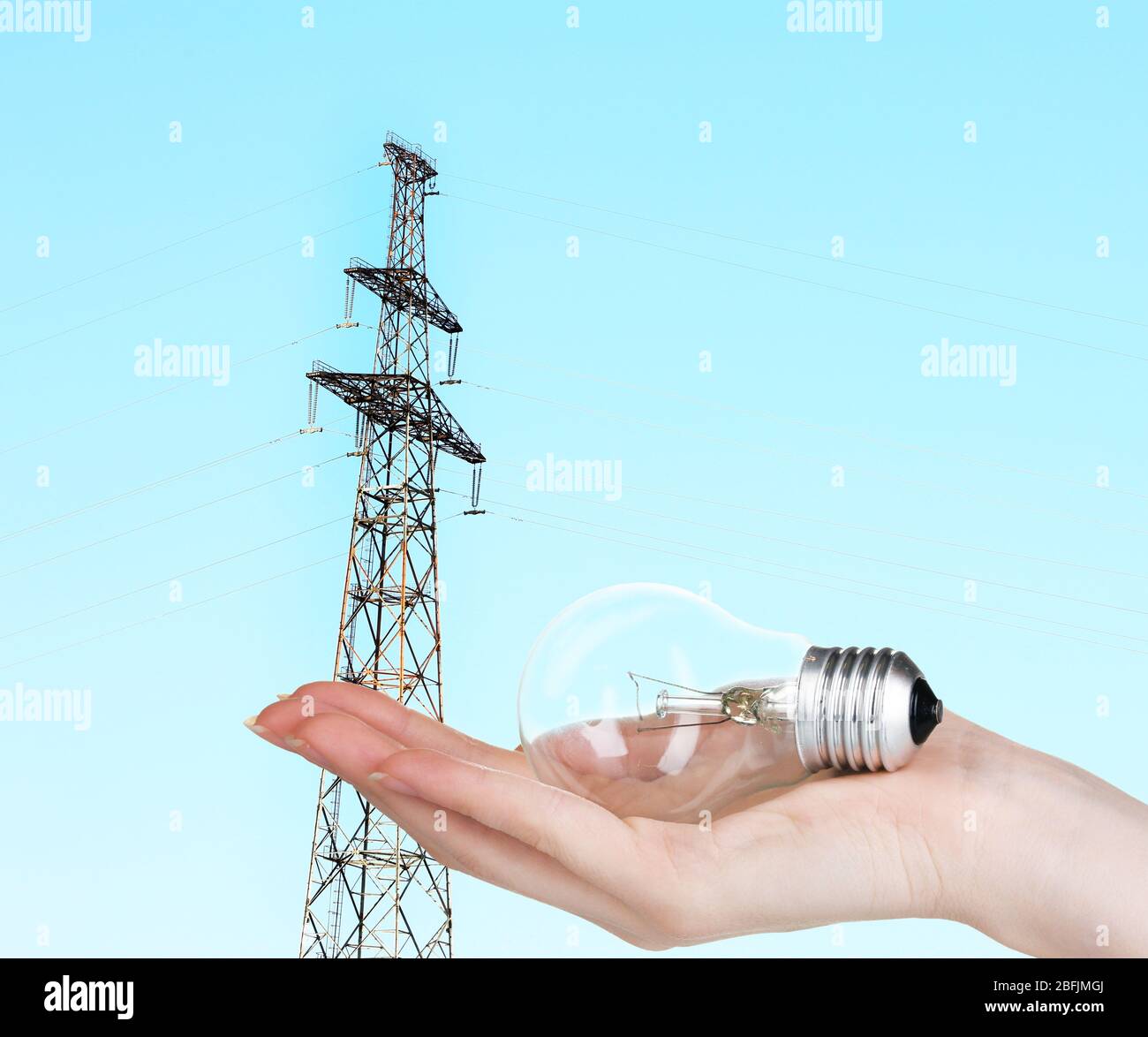 Light bulb in hand on high voltage line background Stock Photo - Alamy