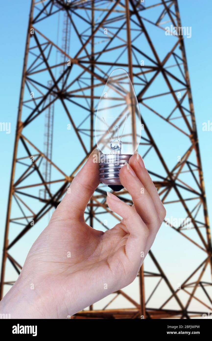 Light bulb in hand on high voltage line background Stock Photo - Alamy