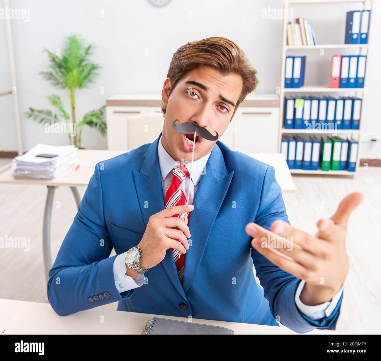 The funny bisinessman with fake moustache in the office Stock Photo - Alamy