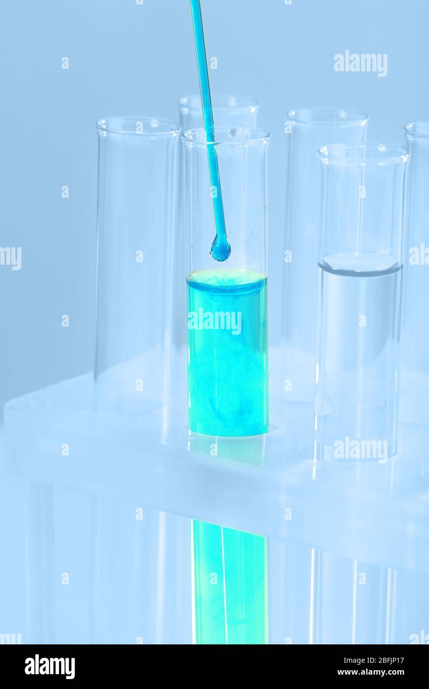 Test-tubes with blue liquid and stick on blue background Stock Photo ...