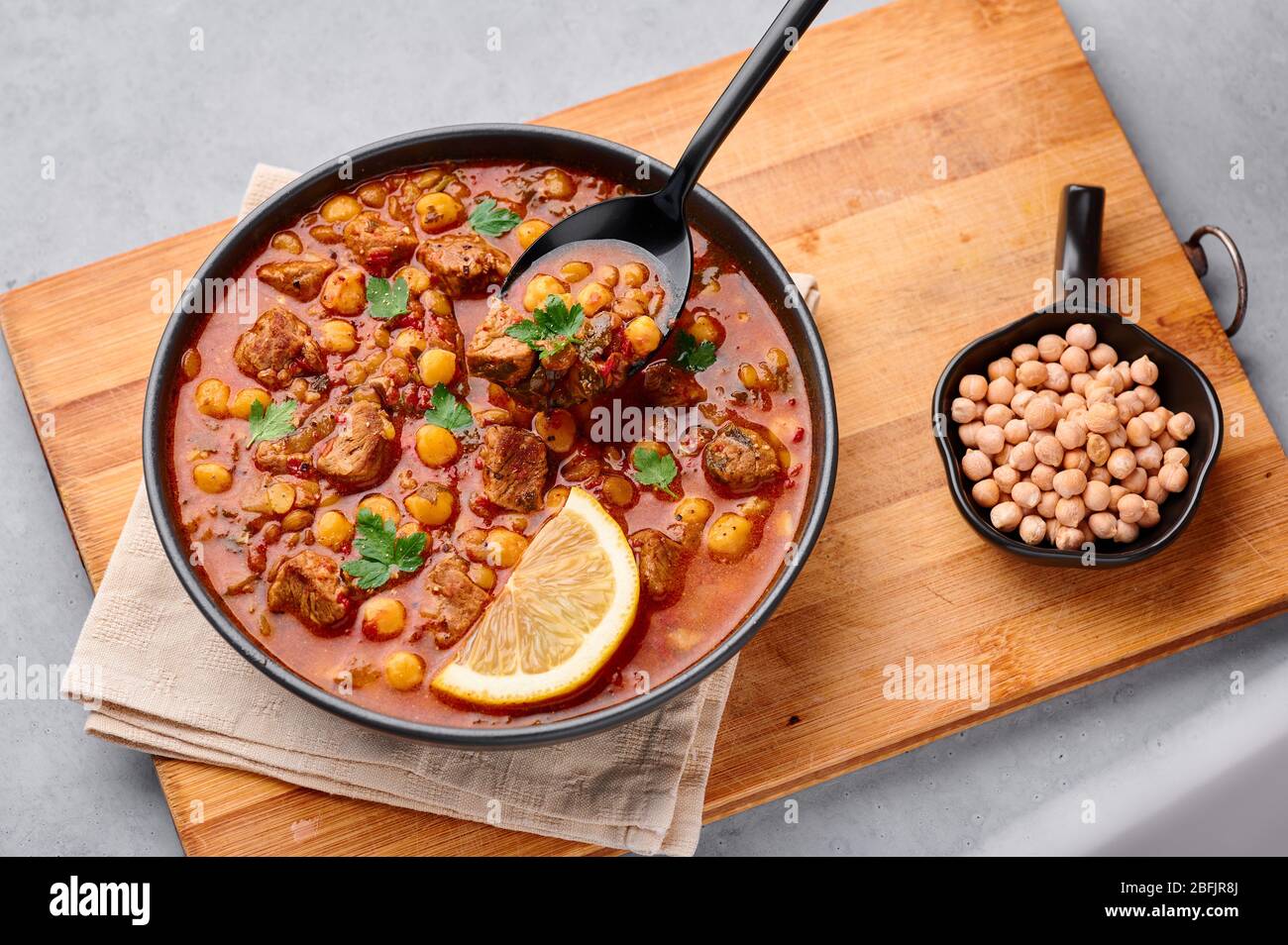 Moroccan Harira Soup in black bowl at grey concrete table top. Harira ...