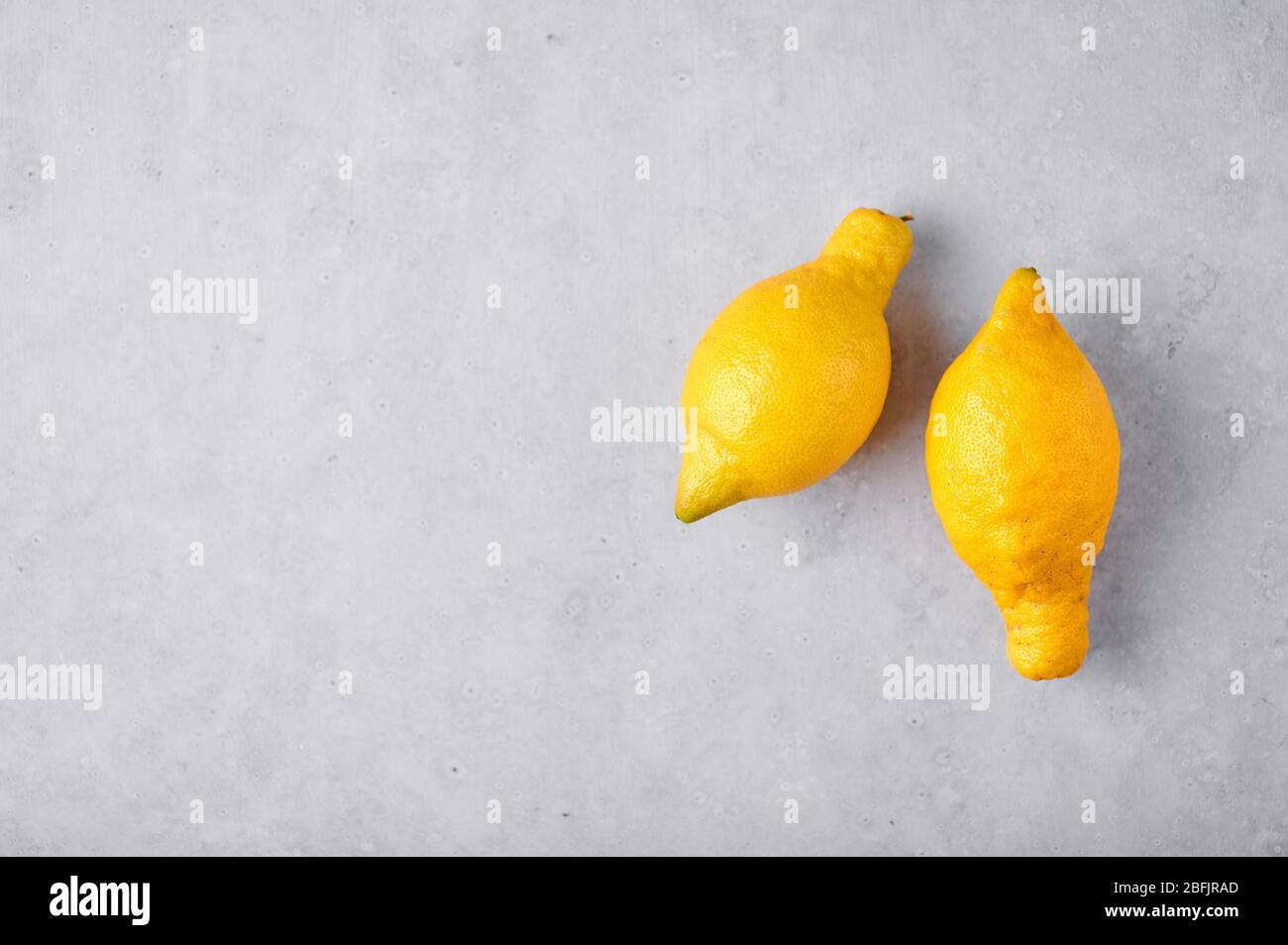 Two imperfect lemons at grey slate background. Ugly Fruits concept ...