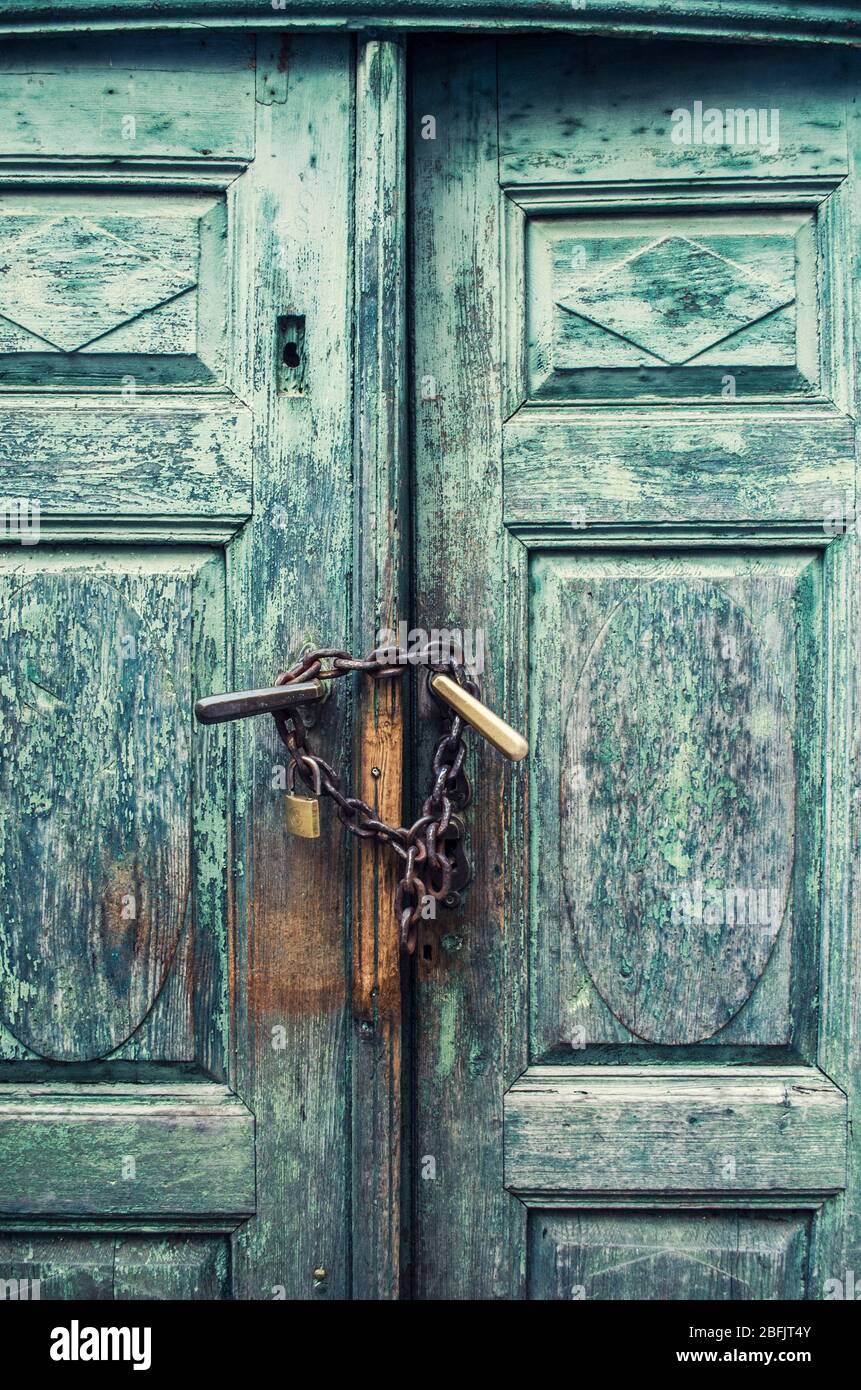 Antique emerald door with craquelures with a chain lock. Quarantine ...
