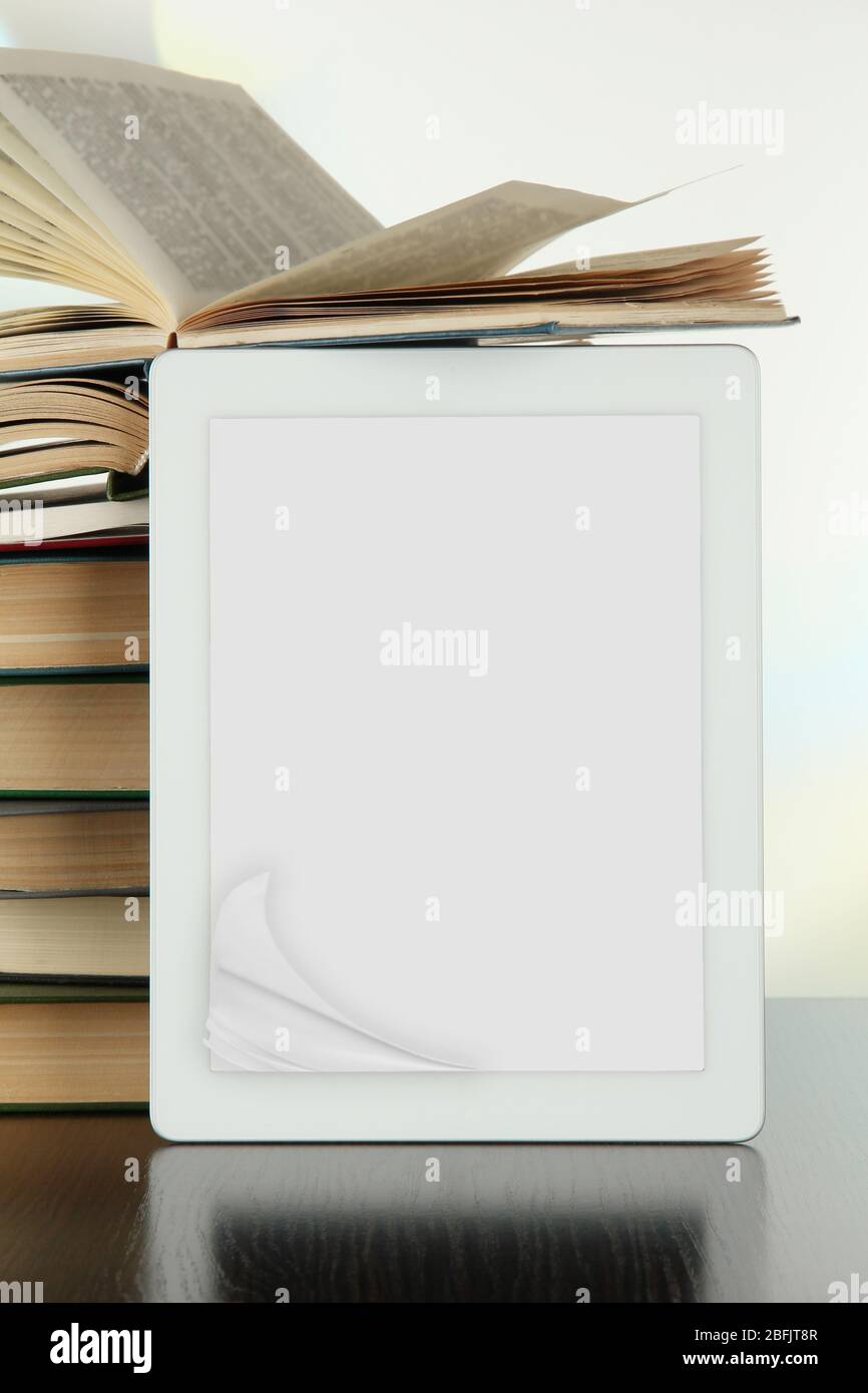 Tablet and books on light background Stock Photo - Alamy