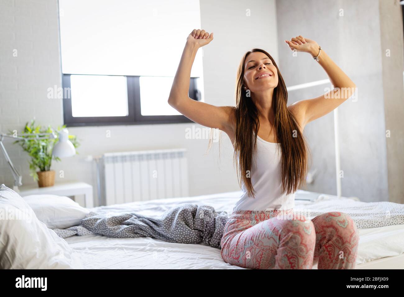 Woman stretching in bed after wake up, entering a day happy and relaxed ...