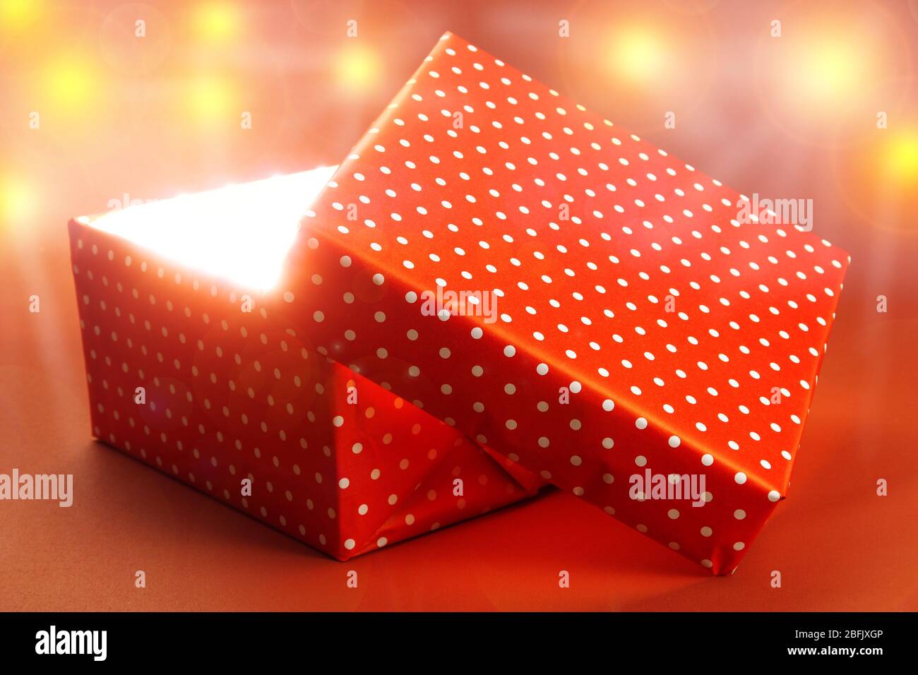 Gift box with bright light on red background Stock Photo - Alamy